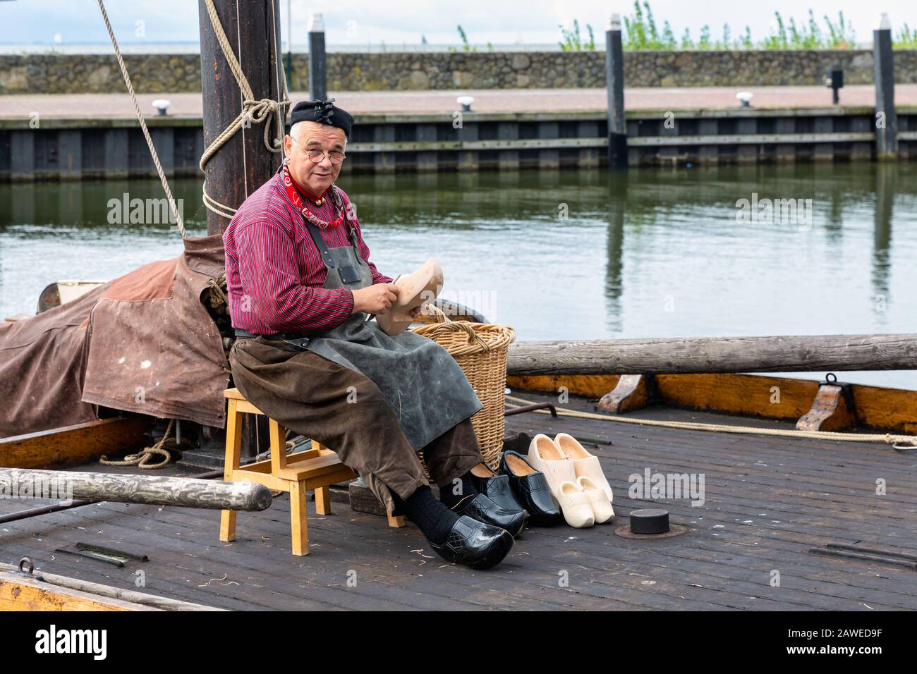 Fisherman in traditional costume making clogs at historic sailing ship ...