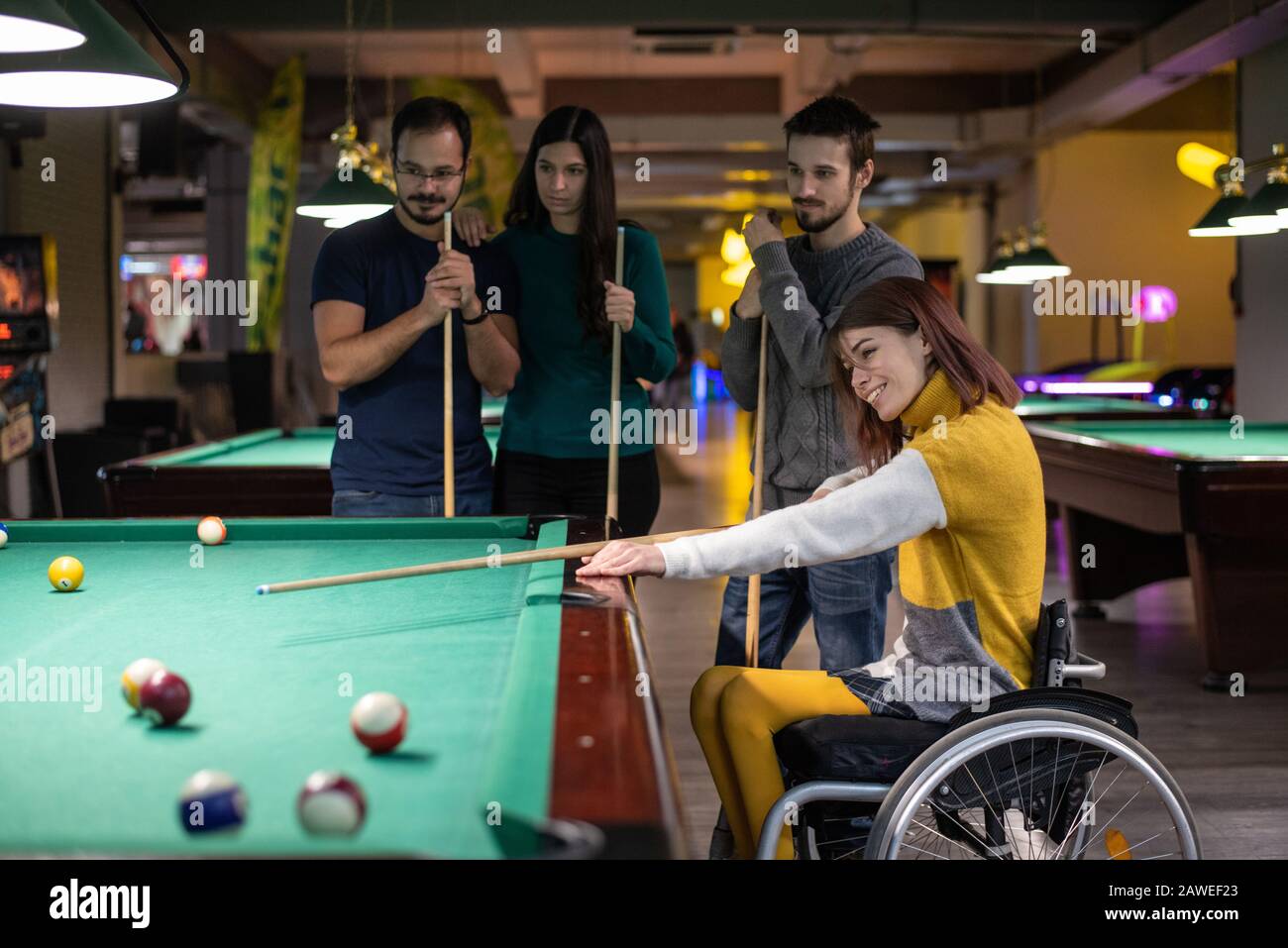 Disabled woman in a wheelchair playing billiards with friends Stock ...