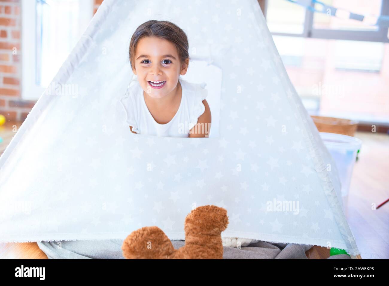 Adorable toddler sitting on the floor inside tipi around lots of toys ...