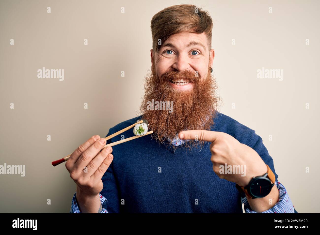 Redhead Irish man with beard eating green maki sushi using chopsticks ...