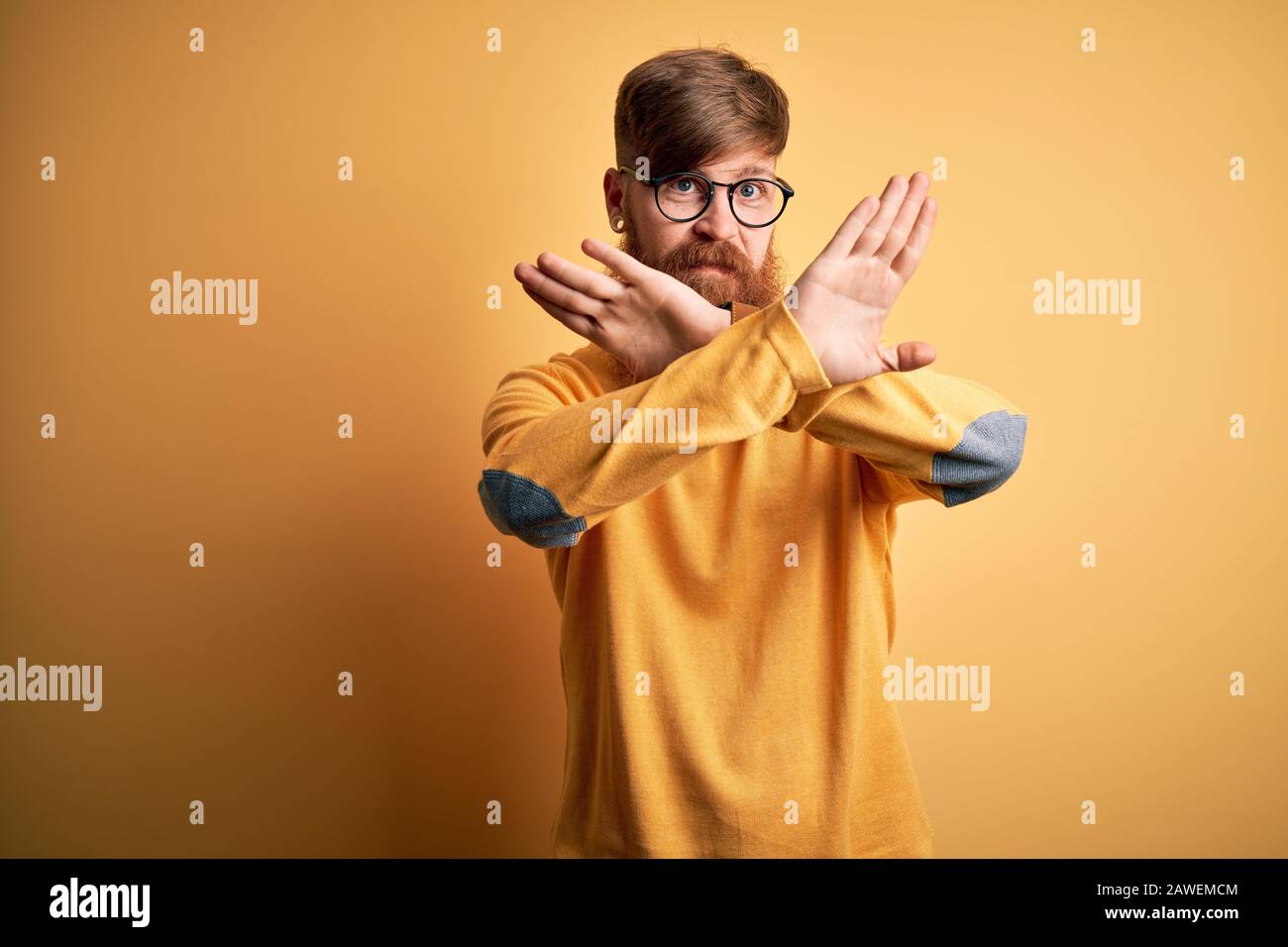 Handsome Irish redhead man with beard wearing glasses over yellow ...