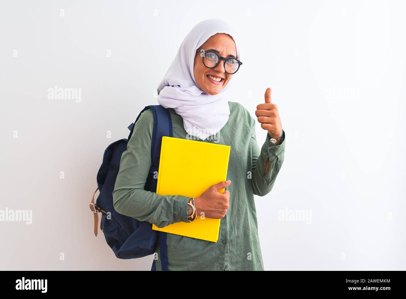Young Arab student woman wearing hijab and backpack holding a book over ...