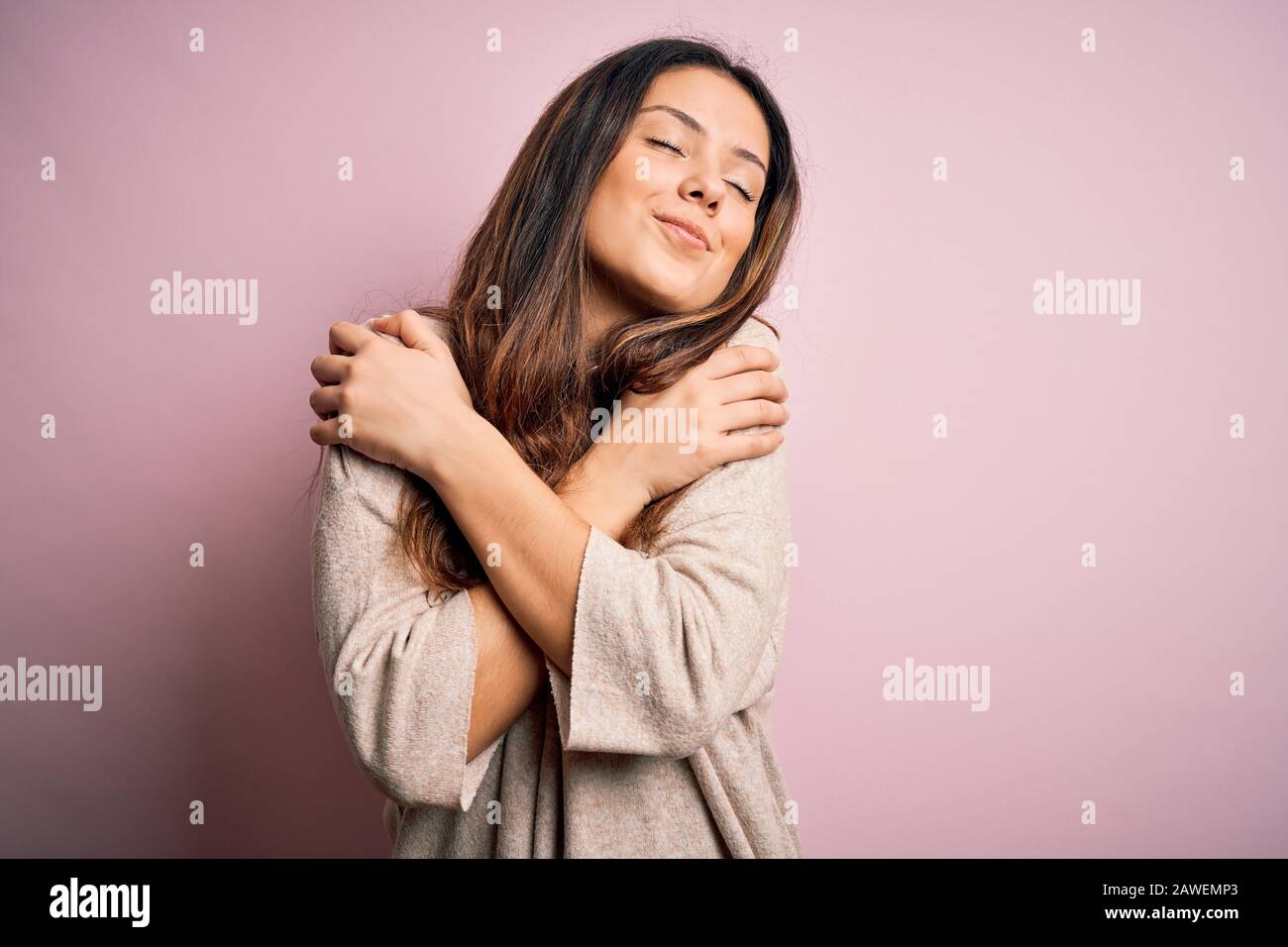 Young beautiful brunette woman wearing casual sweater standing over ...