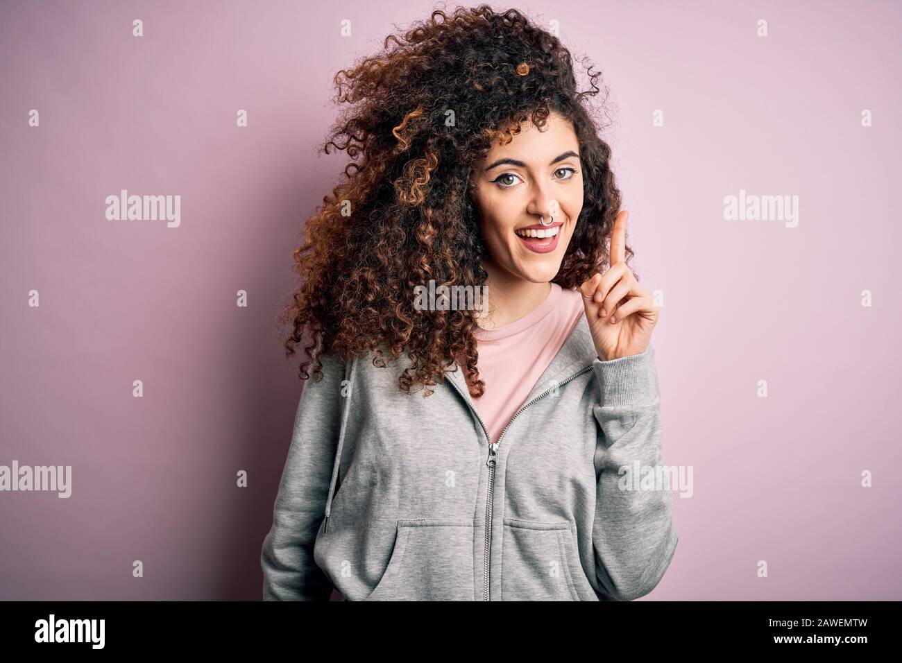 Young beautiful brunette sportswoman with curly hair and piercing ...