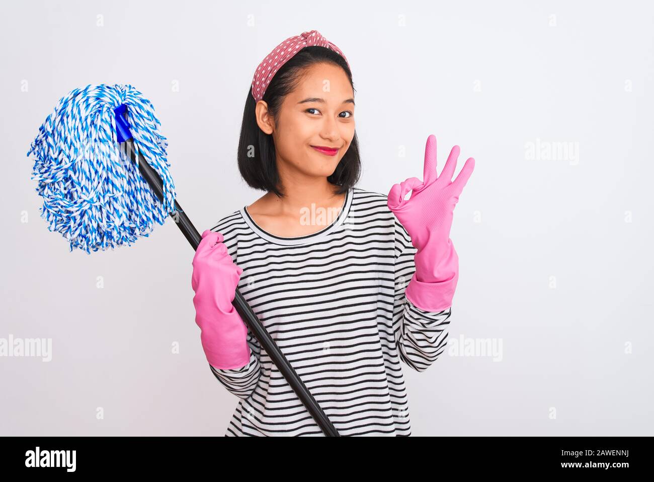 Young chinese cleaner woman wearing gloves holding mop over isolated ...