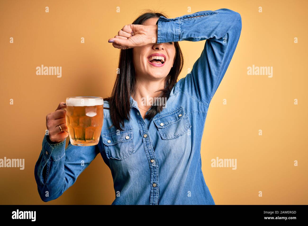 Young woman with blue eyes drinking jar of beer standing over isolated ...