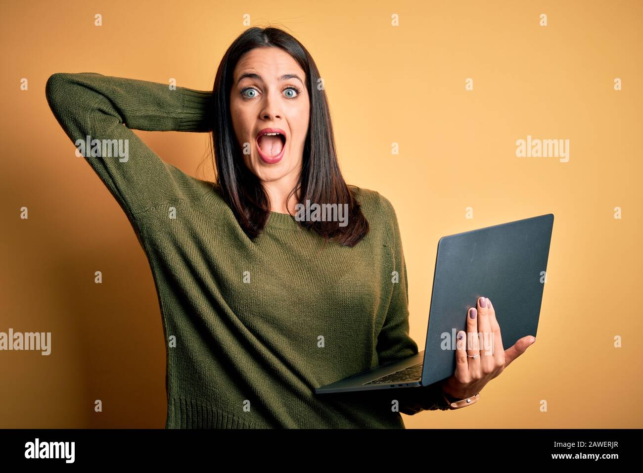 Young brunette woman with blue eyes working using computer laptop over ...