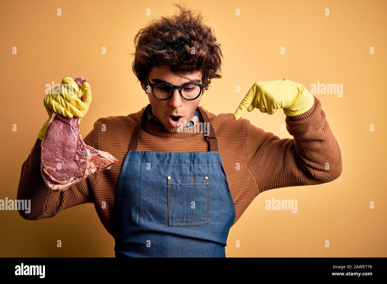 Young handsome butcher man holding meet steak standing over isolated ...