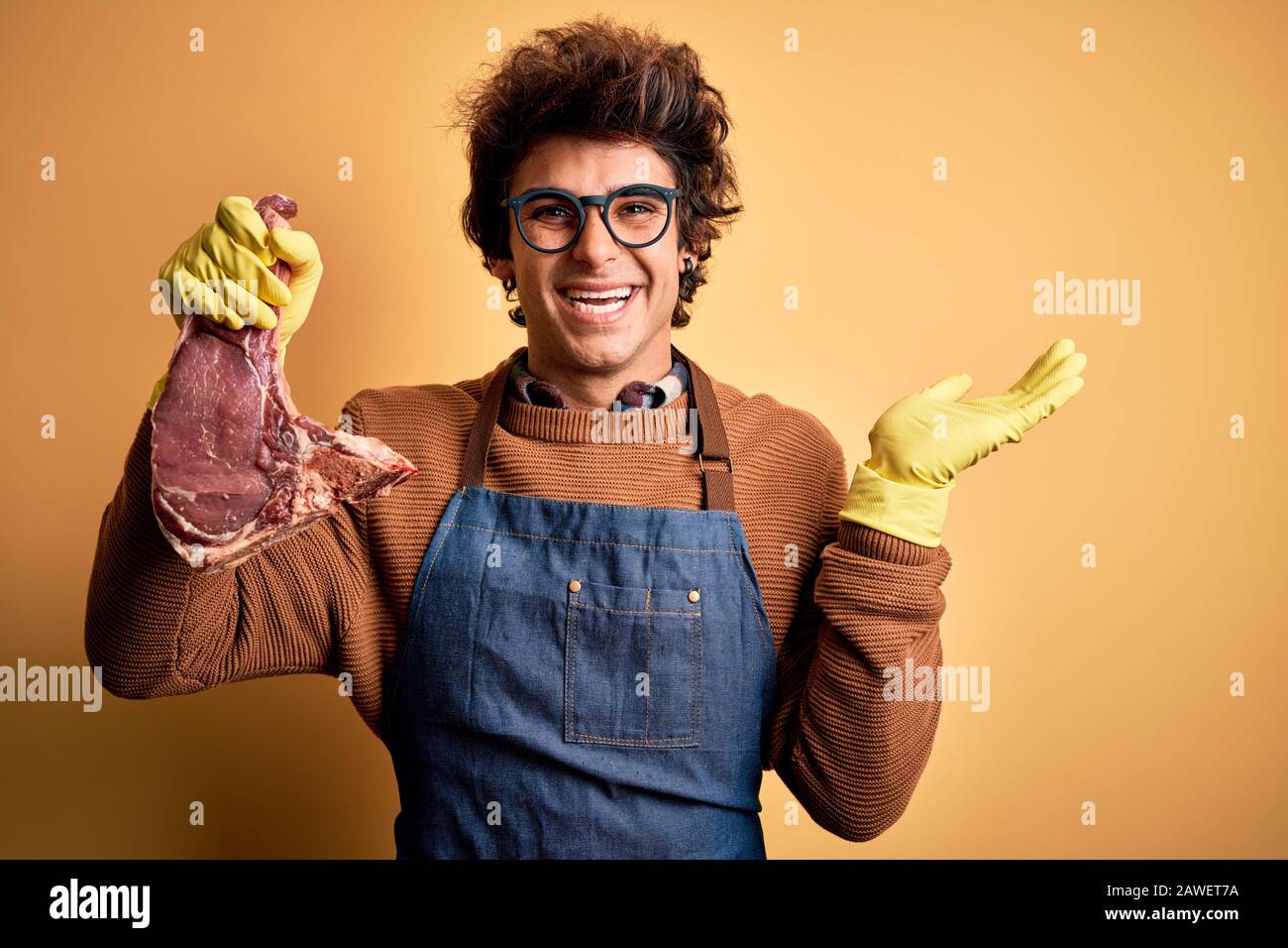 Young handsome butcher man holding meet steak standing over isolated ...