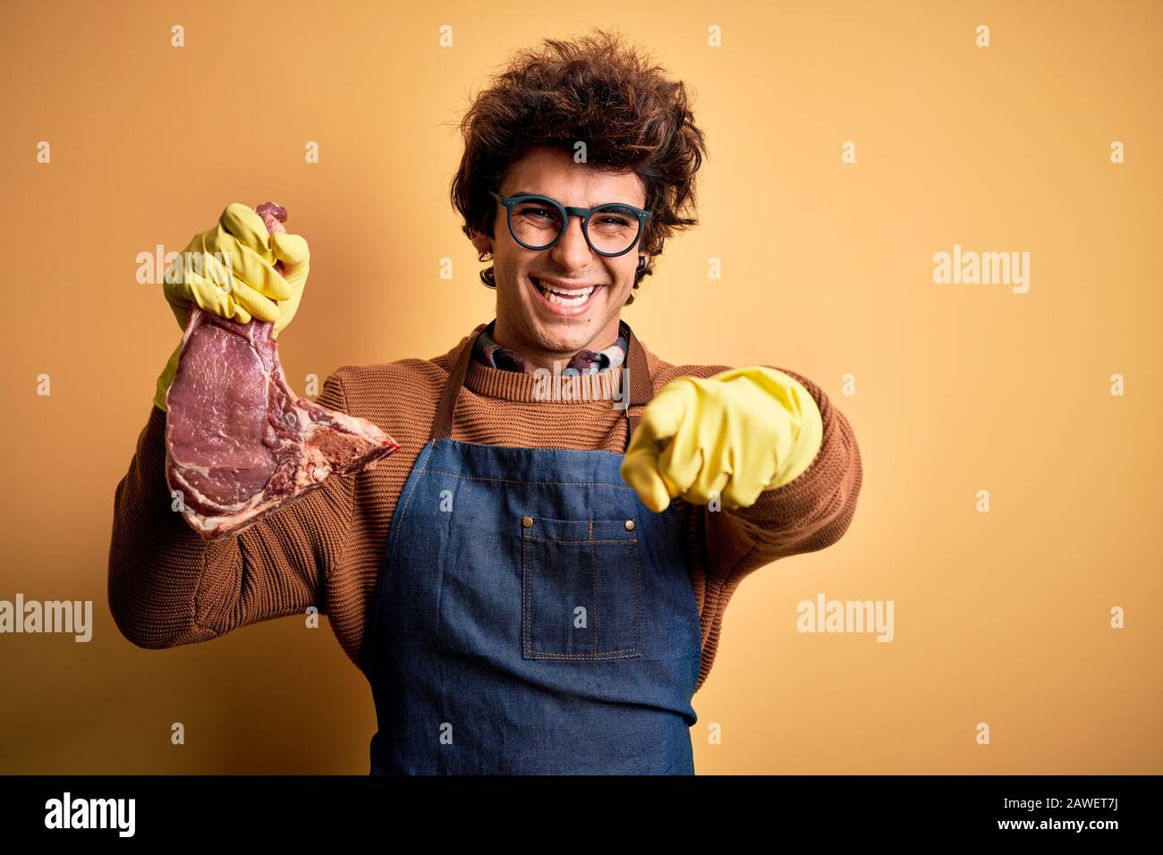 Young handsome butcher man holding meet steak standing over isolated ...