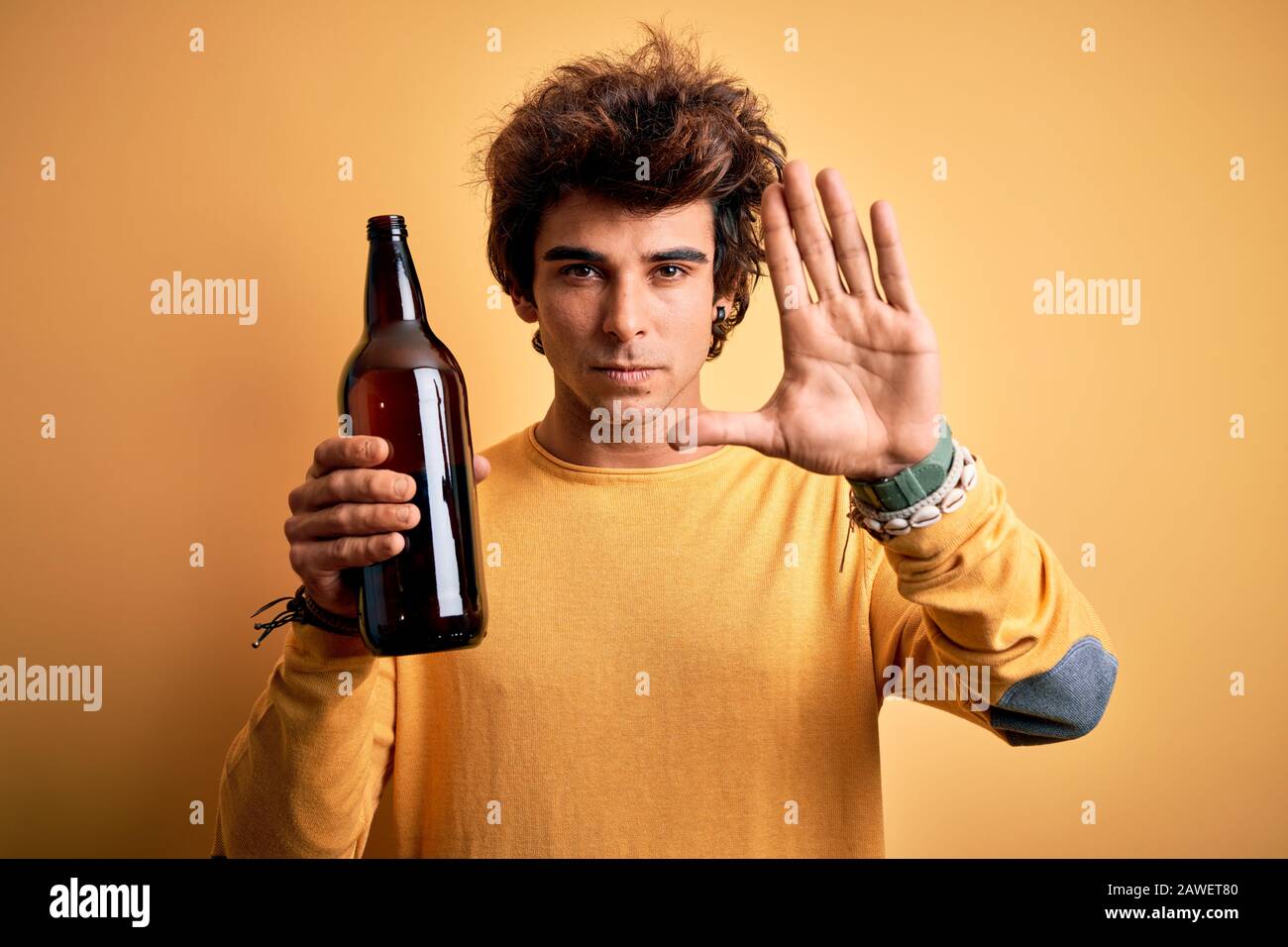 Young handsome man drinking bottle of beer standing over isolated ...