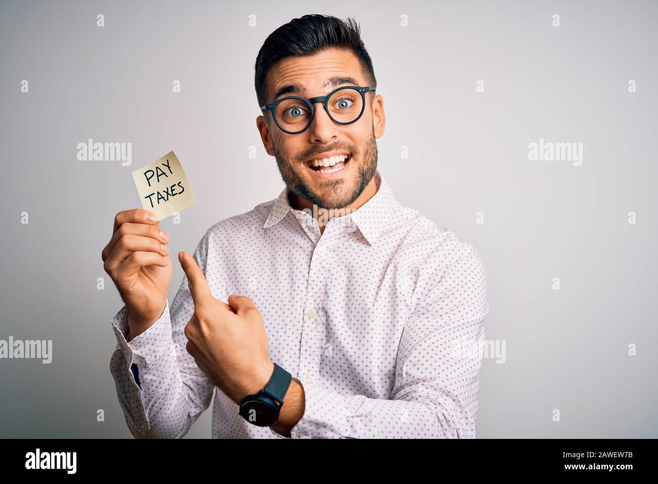 Young handsome man holding reminder paper with pay taxes message over ...