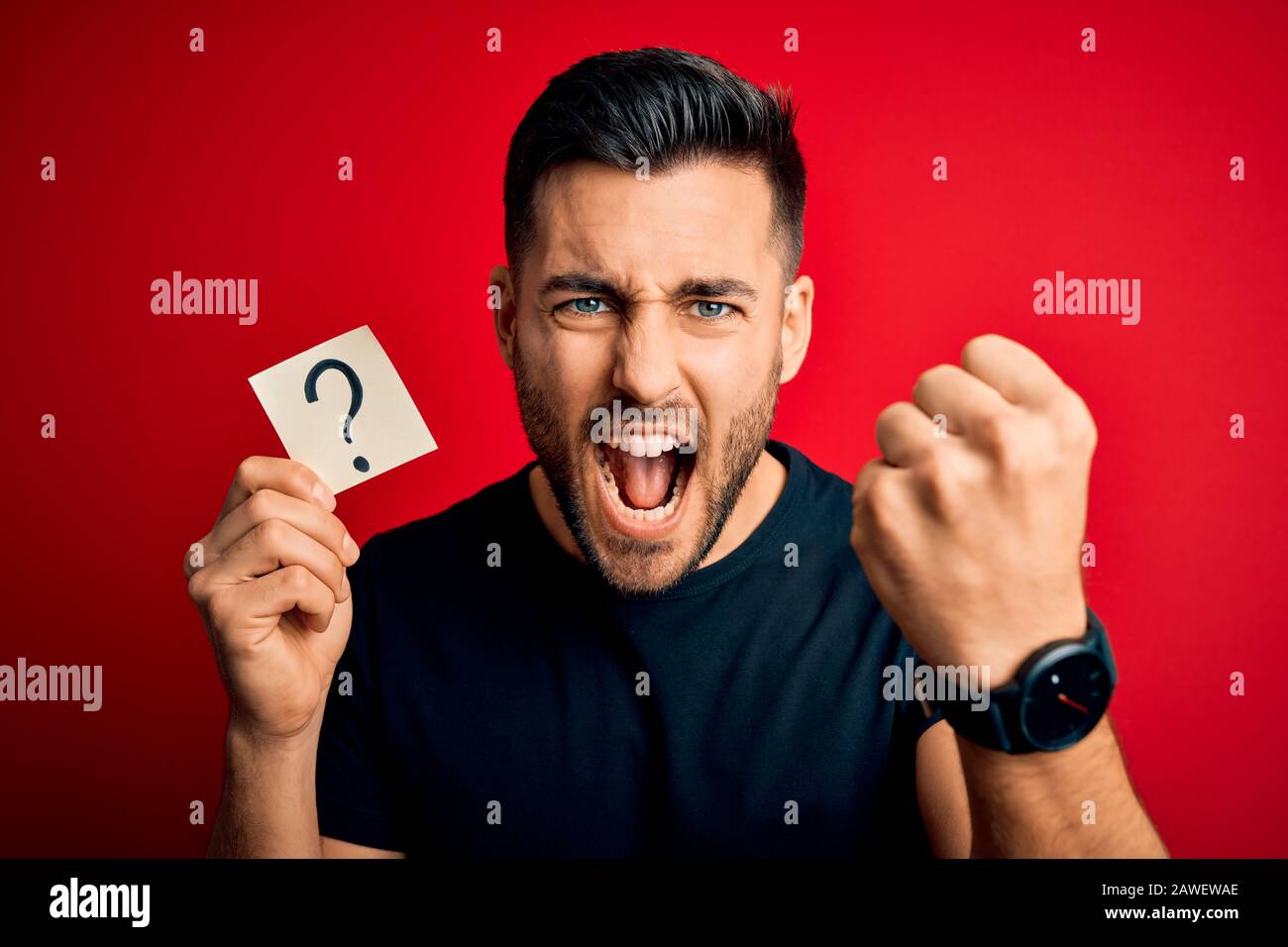 Young handsome man holding paper with question mark symbol over red ...