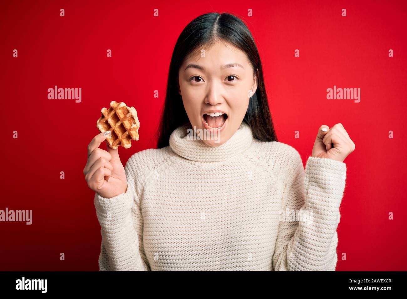Young asian woman eating sweet and tasty belgian waffle over red ...