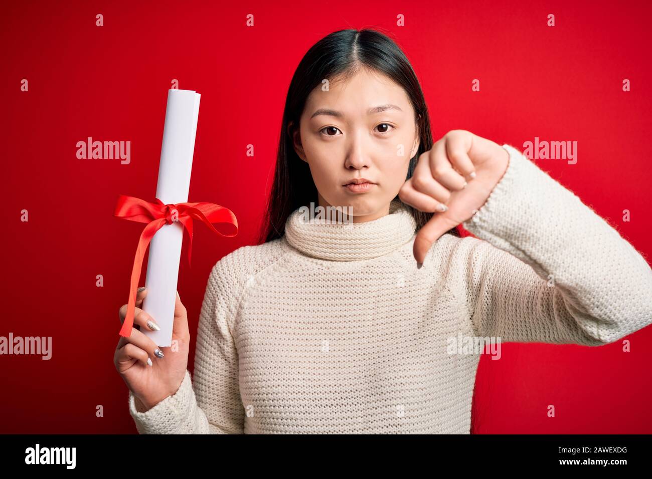Young asian student woman holding graduate diploma over red isolated ...