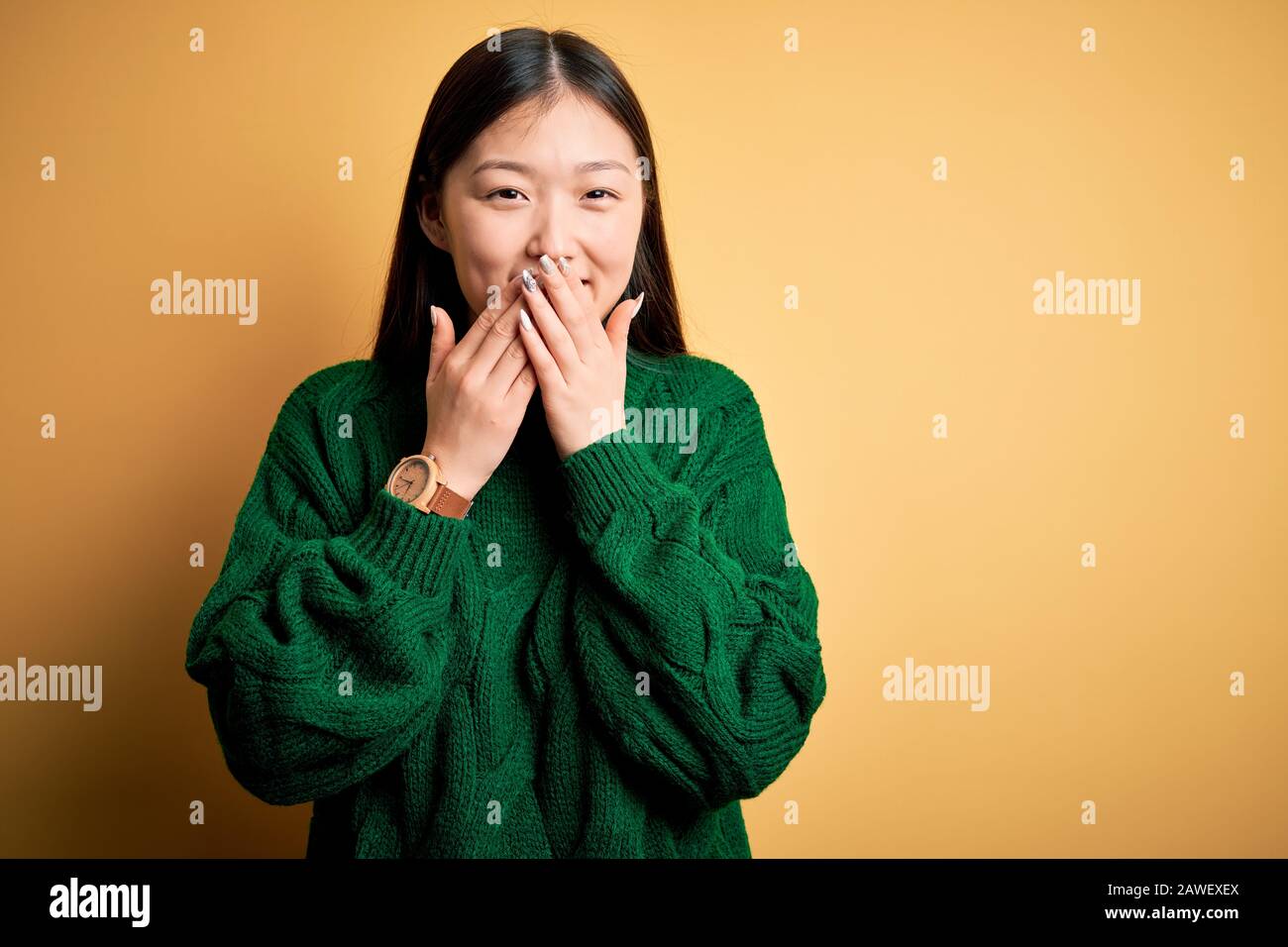 Young Beautiful Asian Woman Wearing Green Winter Sweater Over Yellow