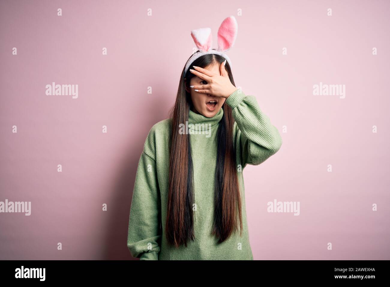 Young asian woman wearing cute easter bunny ears over pink background ...