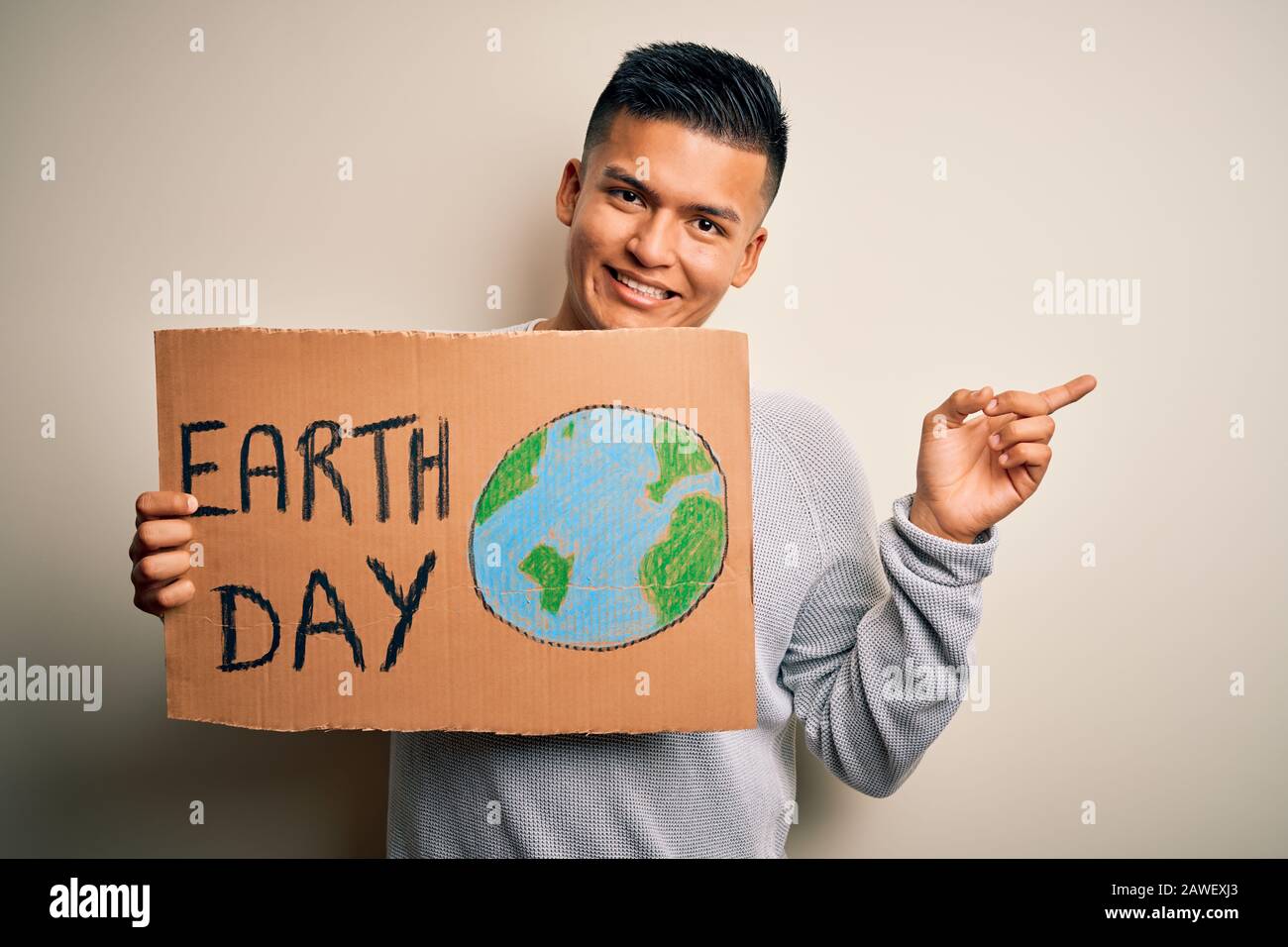 Young handsome latin man holding banner asking for earth and enviroment ...