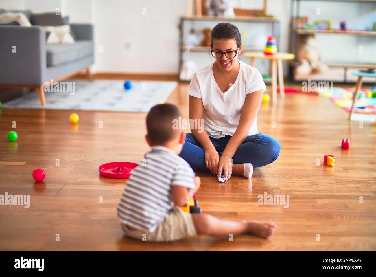 Beautiful teacher and toddler boy playing with tractor and cars at ...