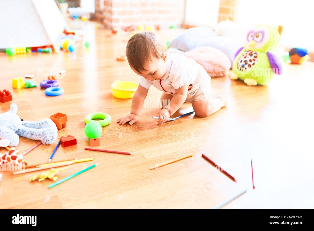 Adorable toddler crawling around lots of toys at kindergarten Stock ...