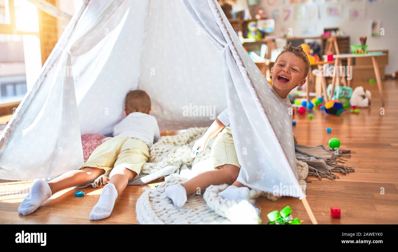 Adorable blonde twins playing inside tipi around lots of toys at ...