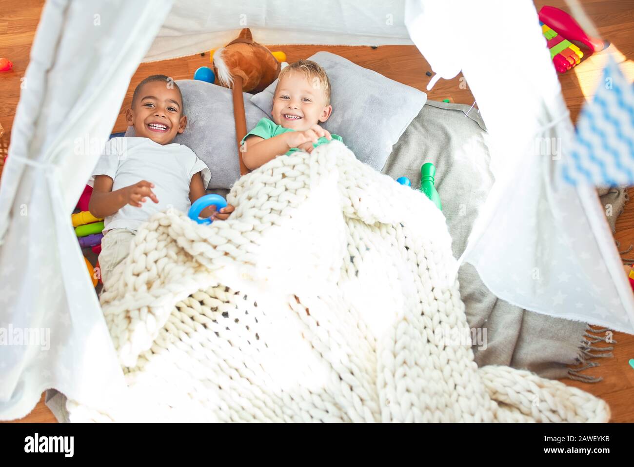Adorable toddlers playing inside tipi around lots of toys at ...