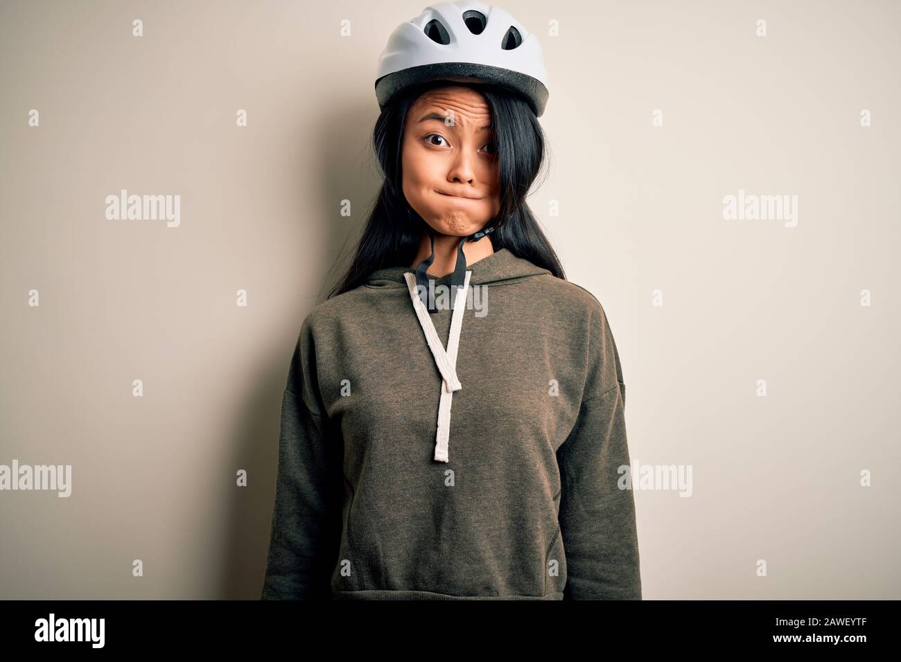 Young beautiful chinese woman wearing bike helmet over isolated white ...