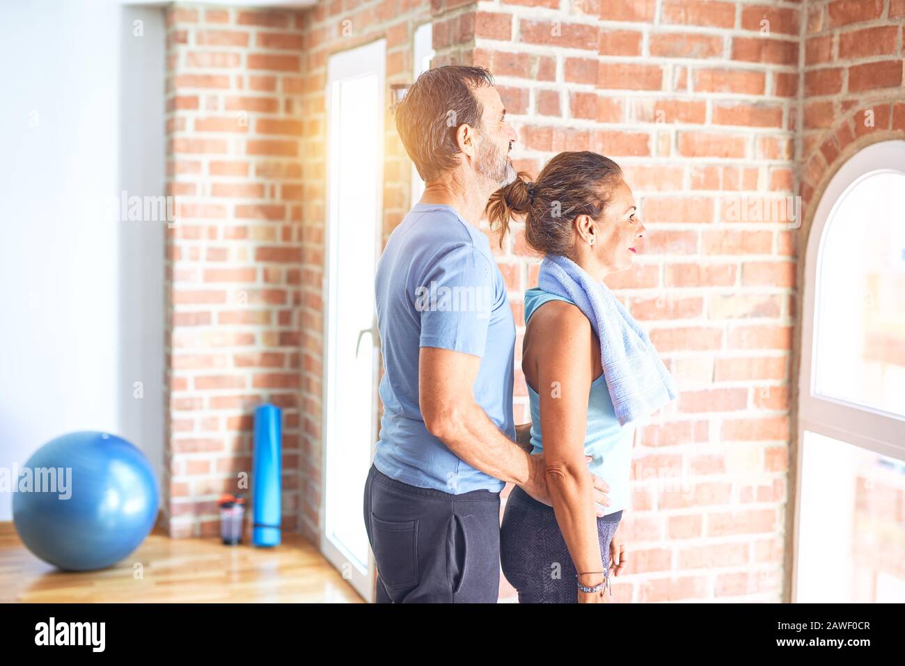 Middle age sporty couple standing before do exercise at gym looking to ...