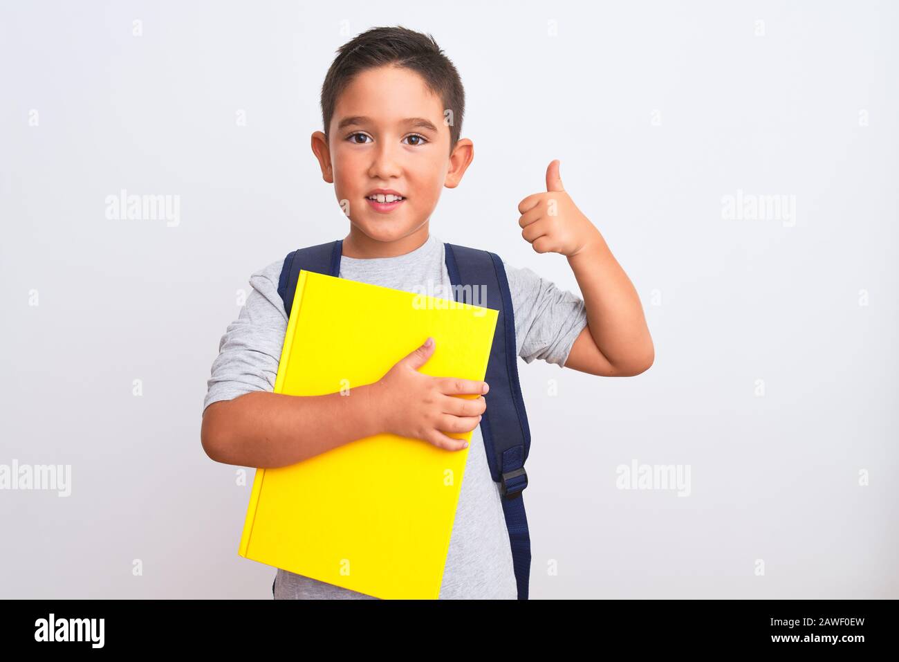 Beautiful student kid boy wearing backpack holding book over isolated ...