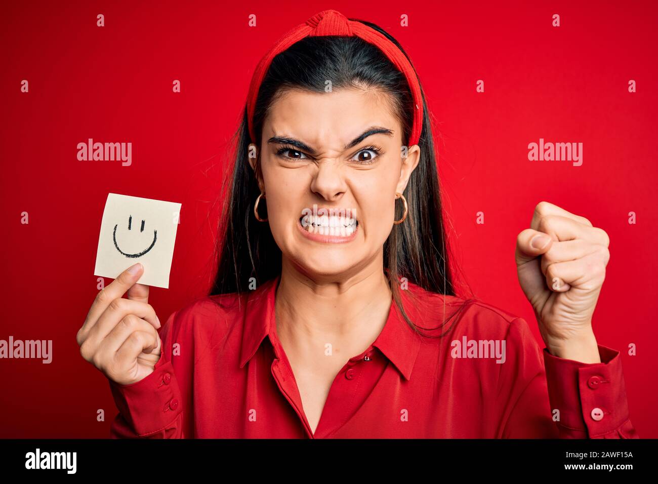 Young beautiful brunette woman holding reminder paper with smile emoji ...