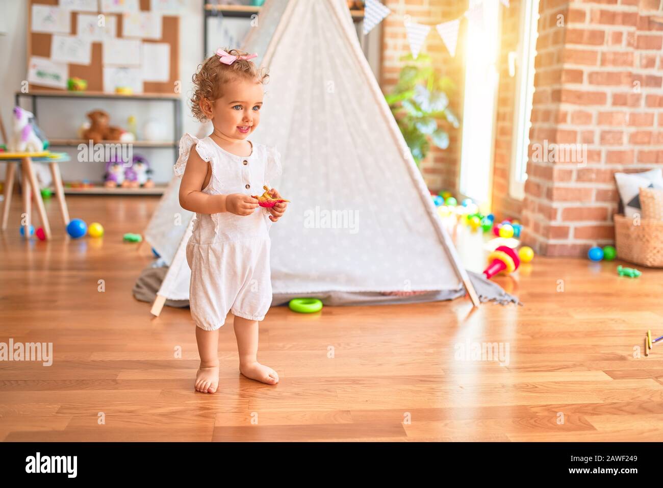 Beautiful caucasian infant playing with toys at colorful playroom ...