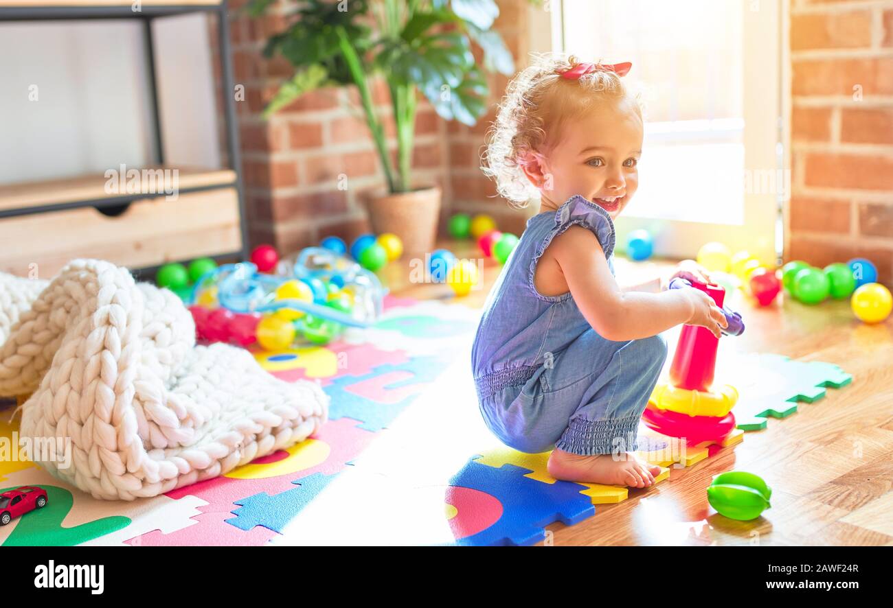 Beautiful caucasian infant playing with toys at colorful playroom ...