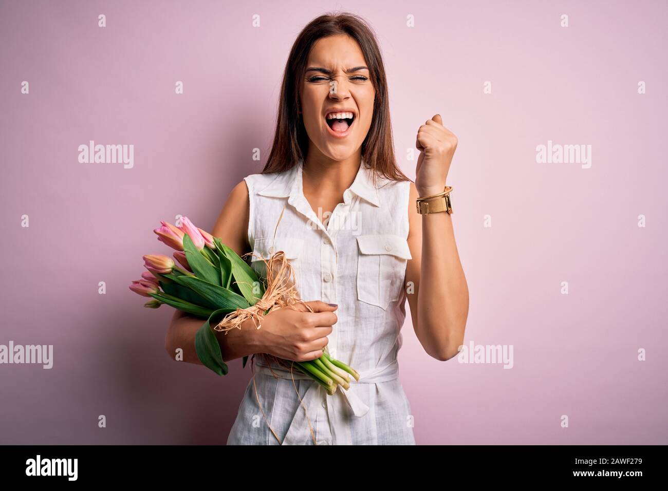 Young beautiful brunette woman holding bouquet of tulips flowers over ...