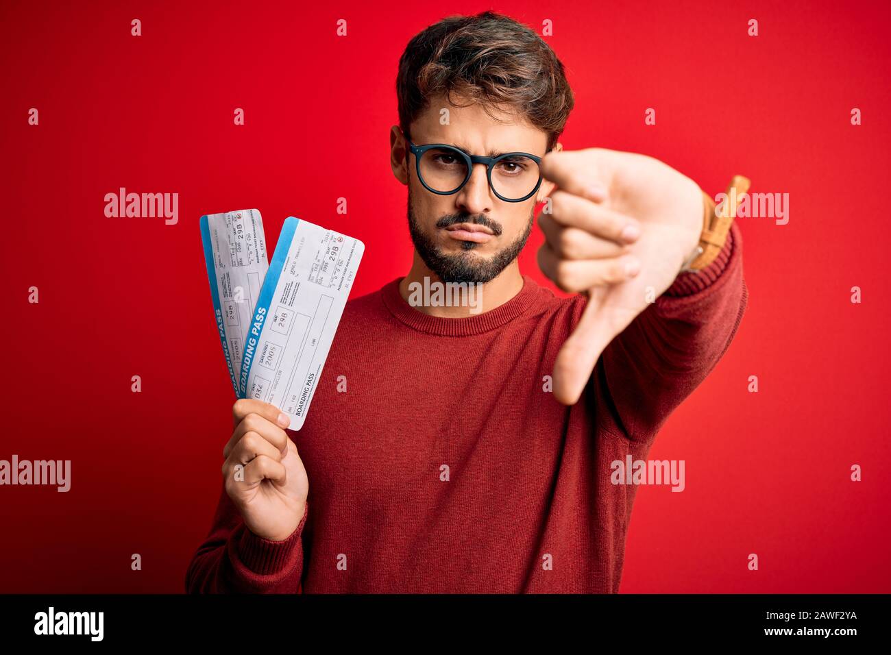 Young tourist man on vacation holding boarding pass standing over red ...