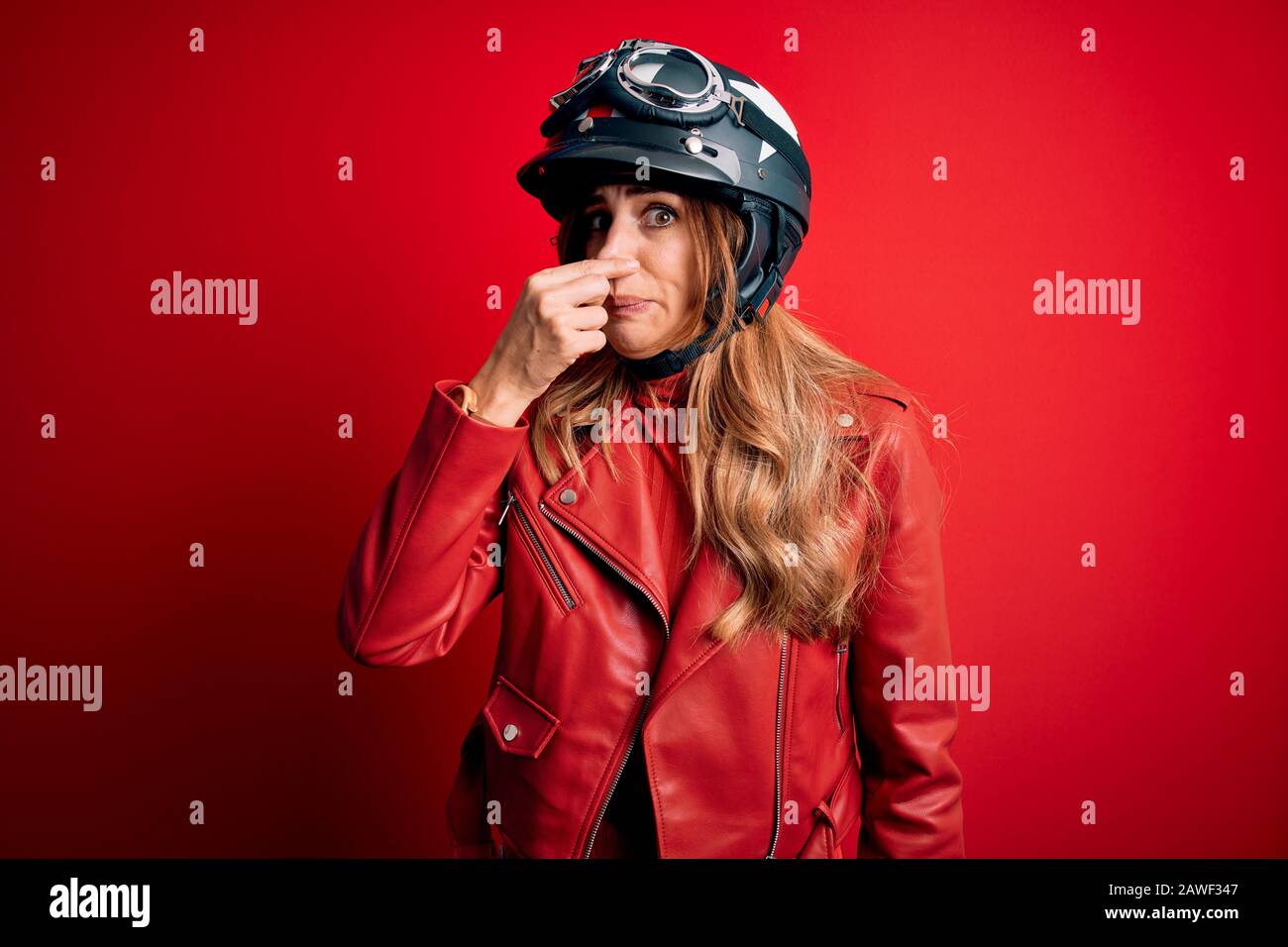 Young beautiful brunette motrocyclist woman wearing moto helmet over ...