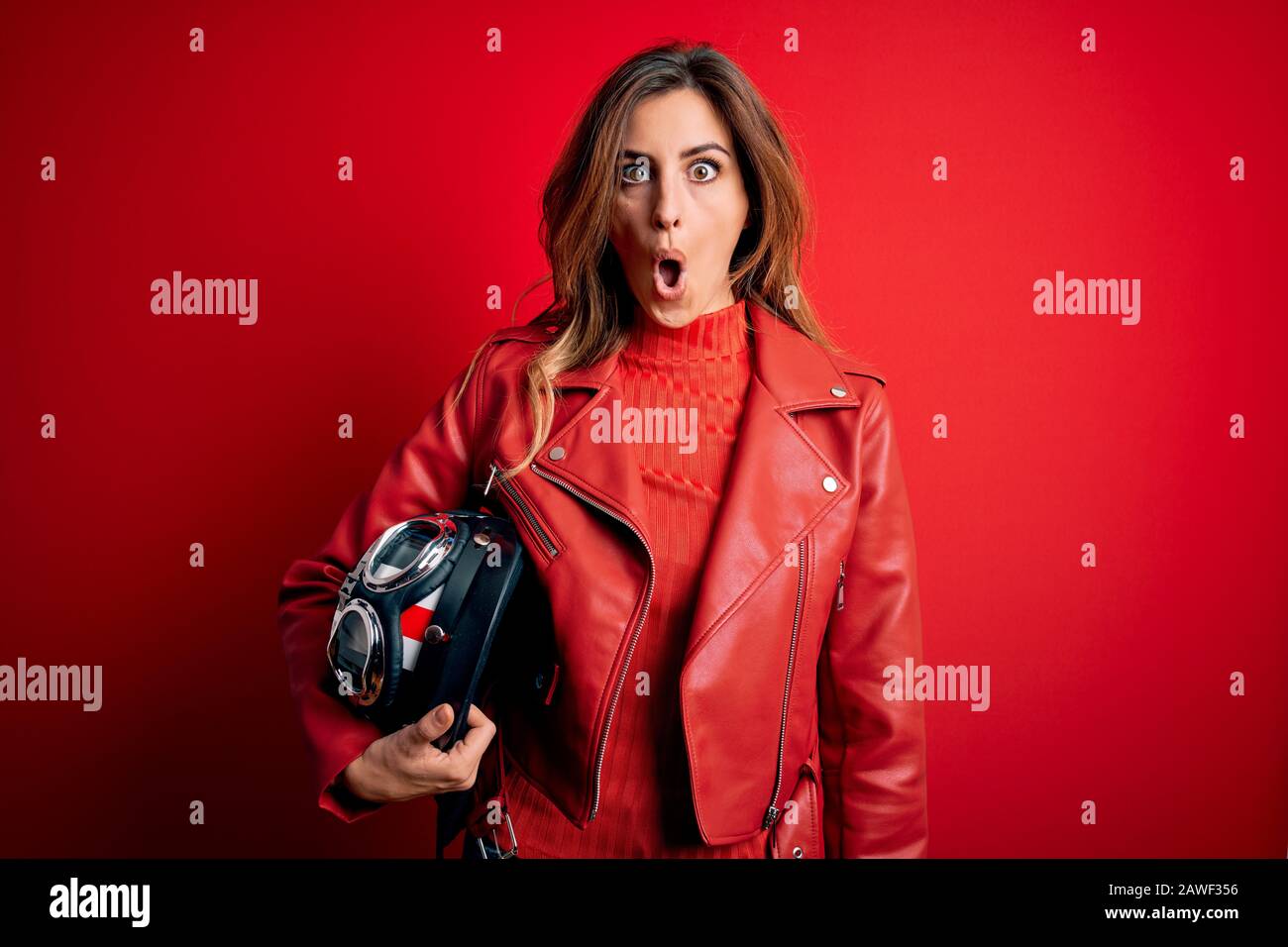 Beautiful brunette motorcyclist woman wearing red jacket holding ...