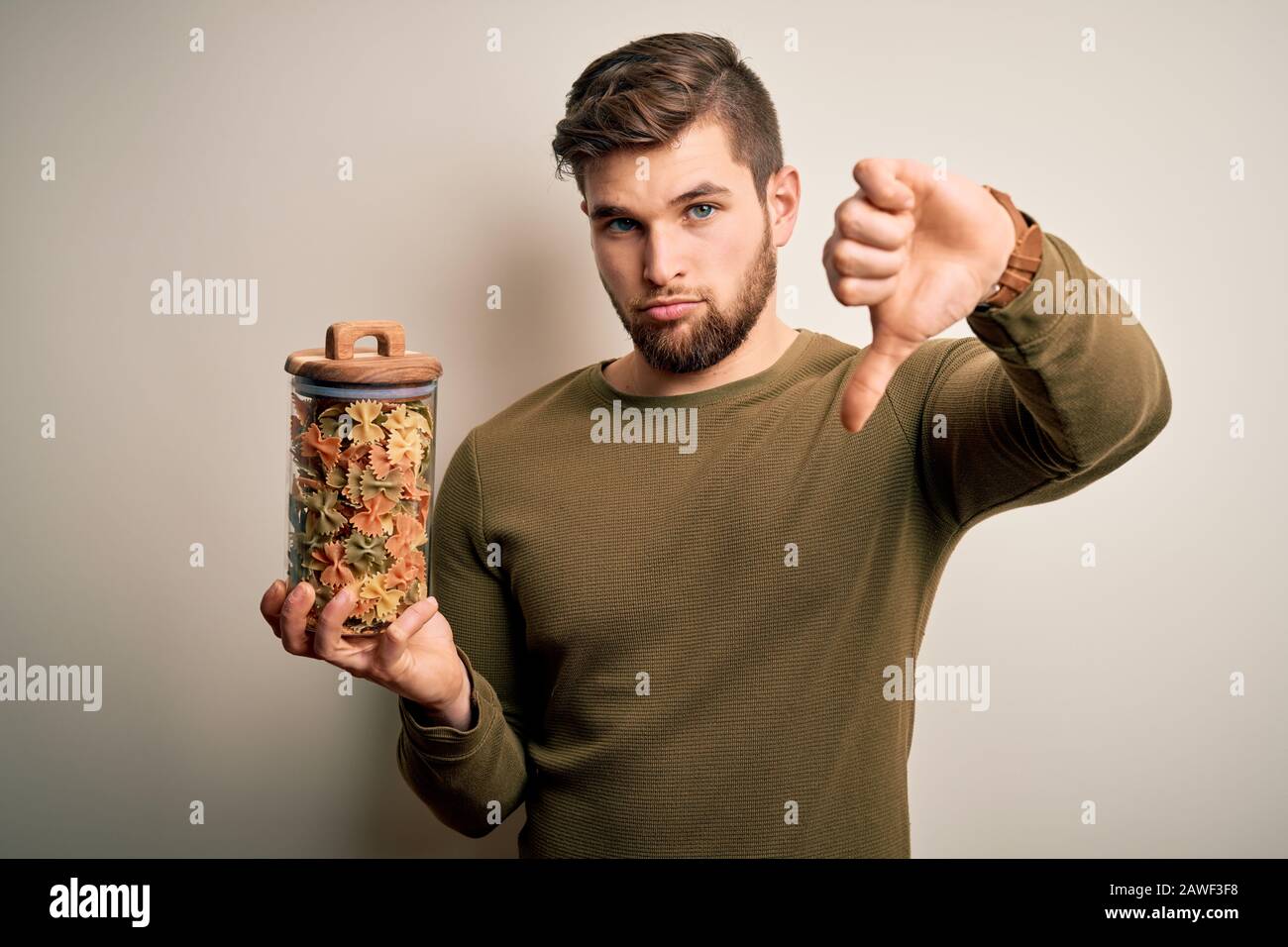Young blond man with beard and blue eyes holding bottle of Italian dry ...