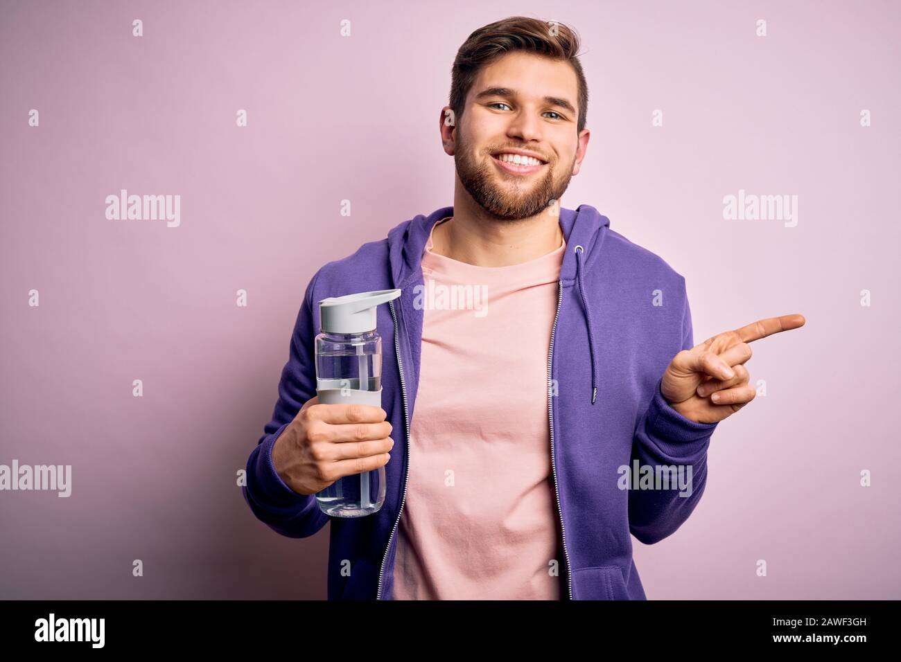 Young blond sporty man with beard and blue eyes doing sport holding ...