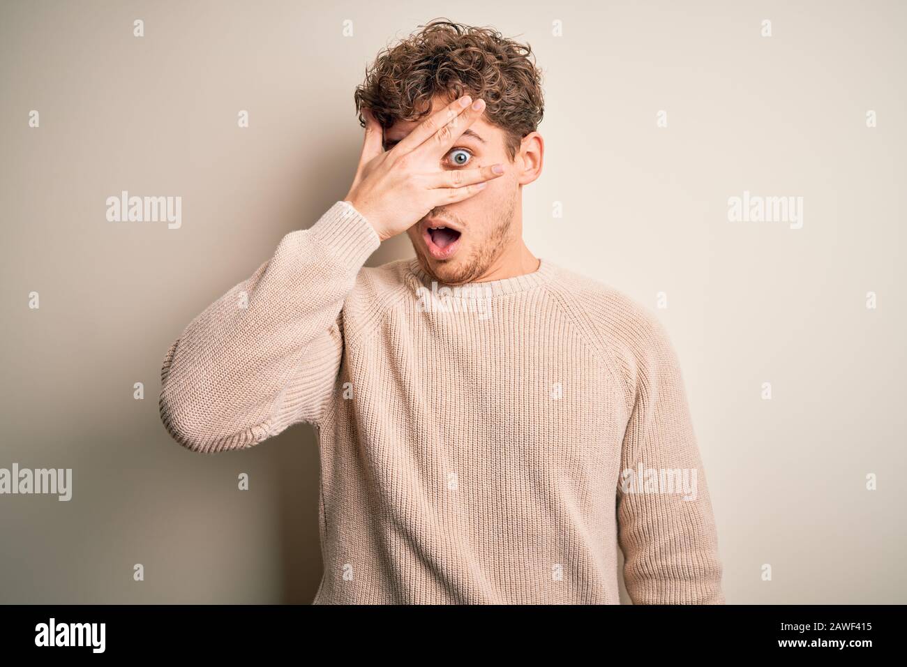 Young blond handsome man with curly hair wearing casual sweater over ...