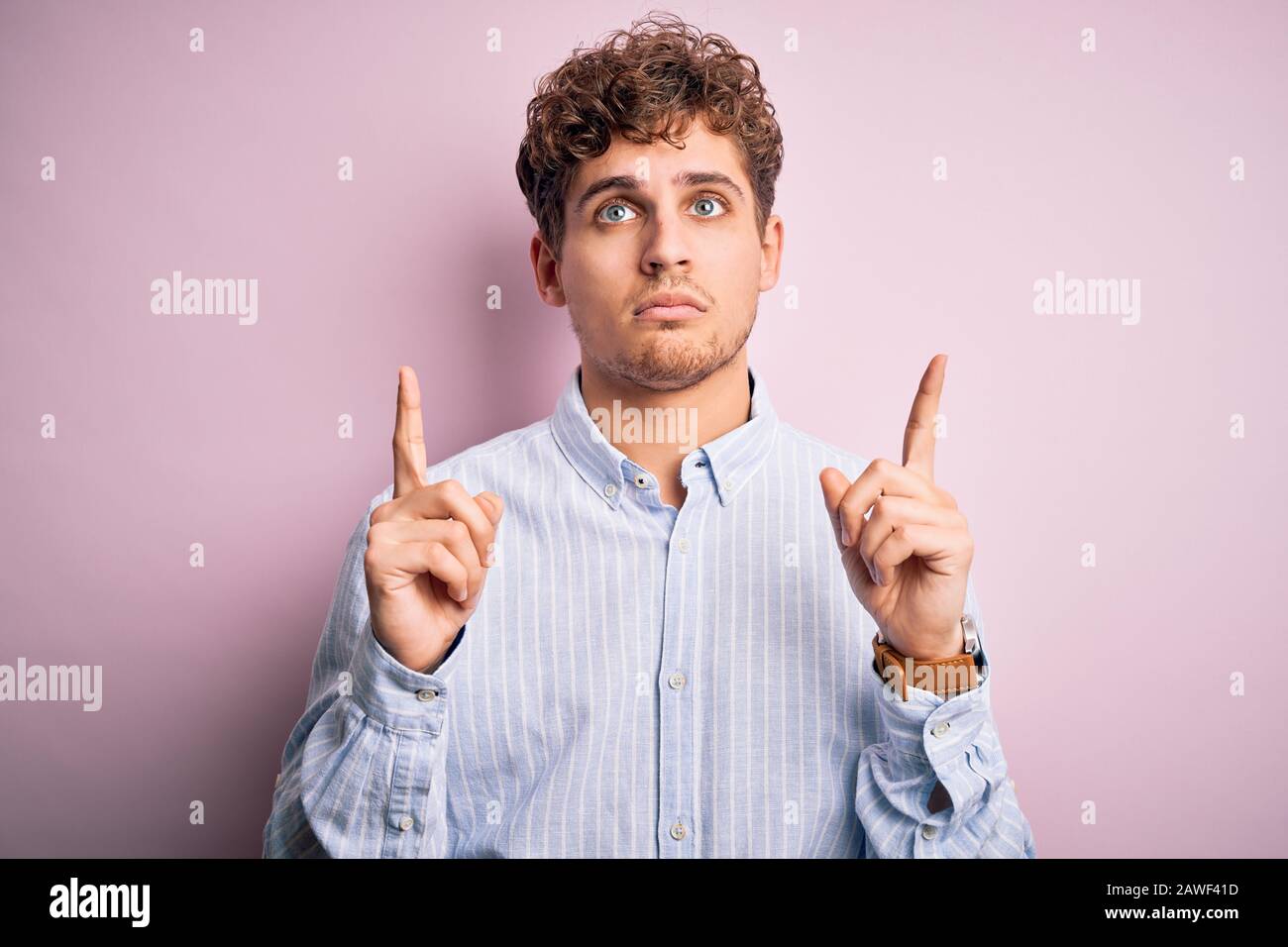 Young blond handsome man with curly hair wearing striped shirt over ...