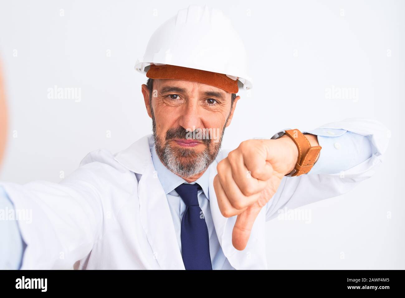 Middle age engineer man wearing helmet make selfie over isolated white ...