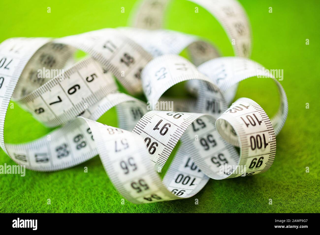 White measuring tape on a green background Stock Photo - Alamy