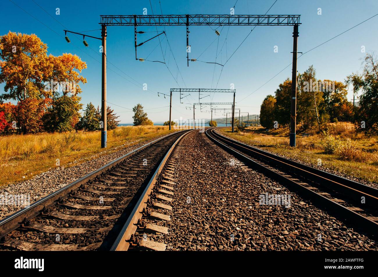 Parallel railway tracks and overhead lines through the forest. autumn ...