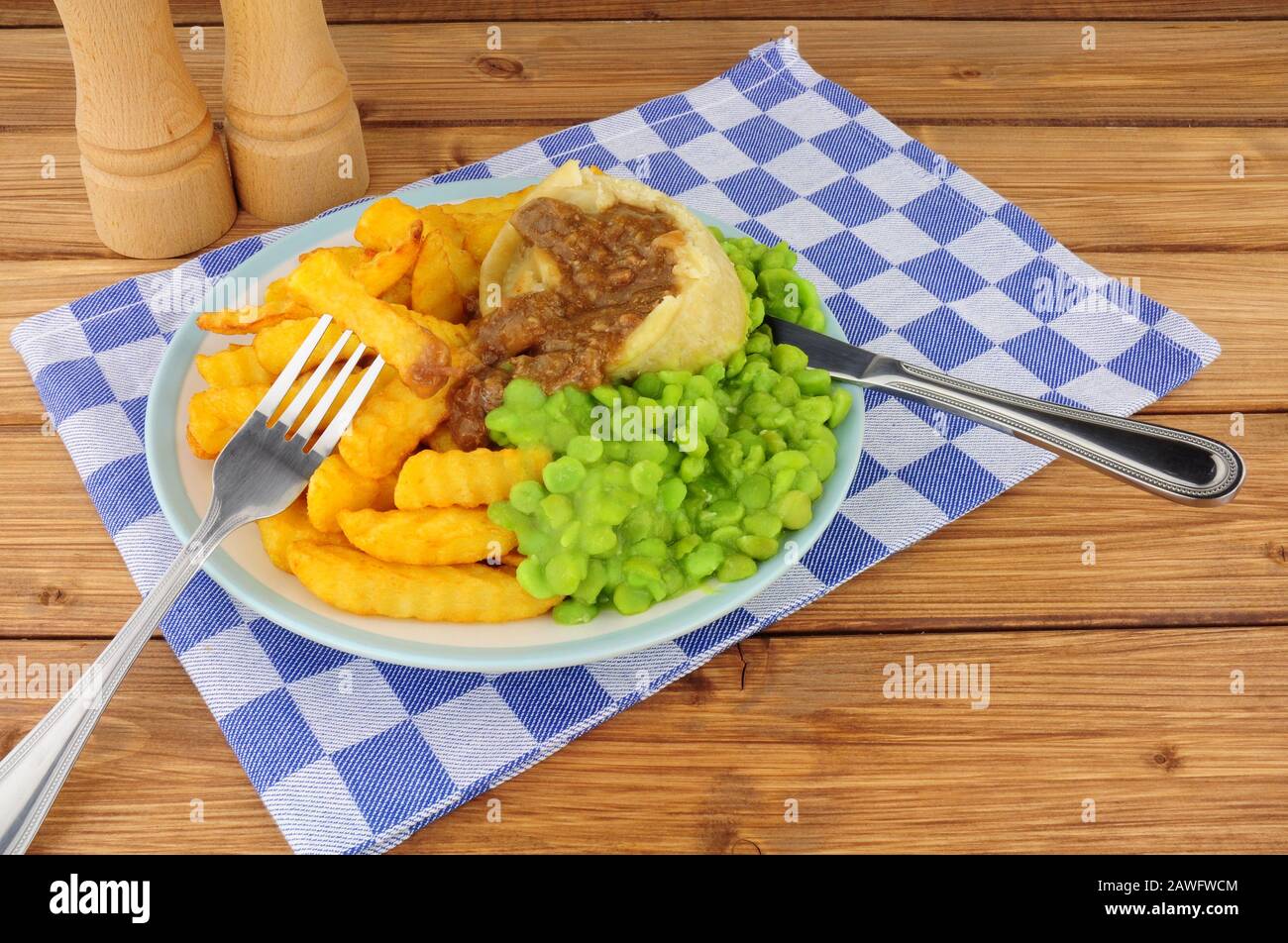 Steak and kidney pudding meal with chips and mushy peas Stock Photo - Alamy