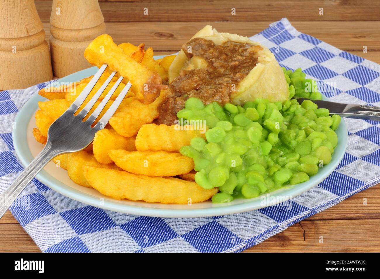 Steak and kidney pudding meal with chips and mushy peas Stock Photo - Alamy