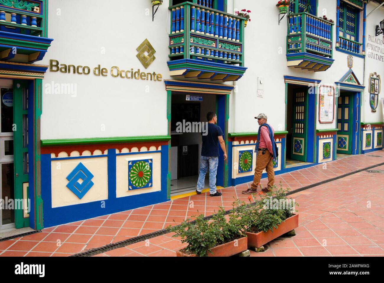 Men standing outside a colonial-style bank and government building ...