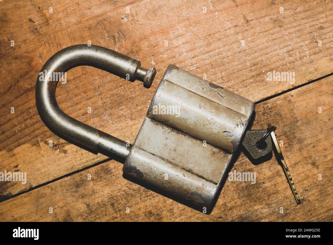 Old rusty lock with a key on a wooden table. Vintage padlock and key on ...