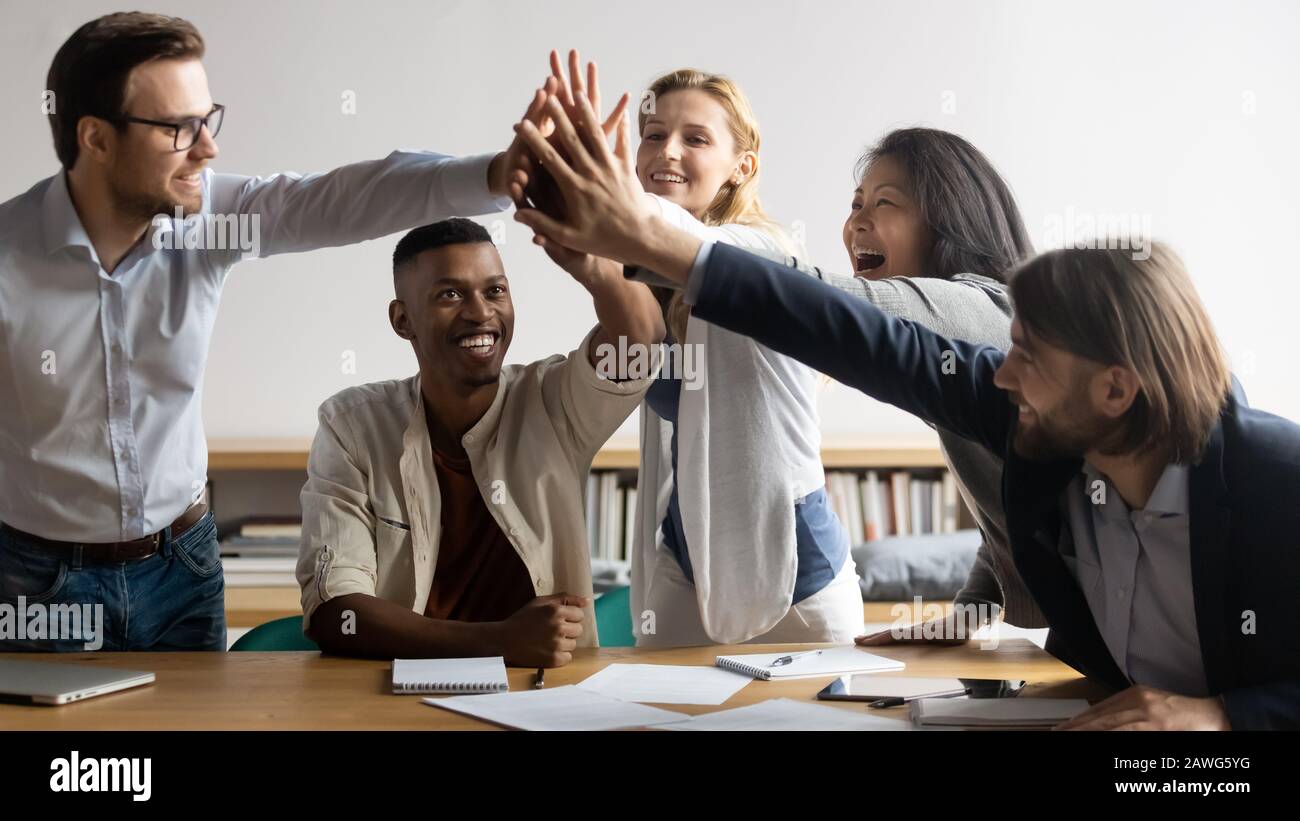 Excited diverse business team giving high five at meeting Stock Photo ...