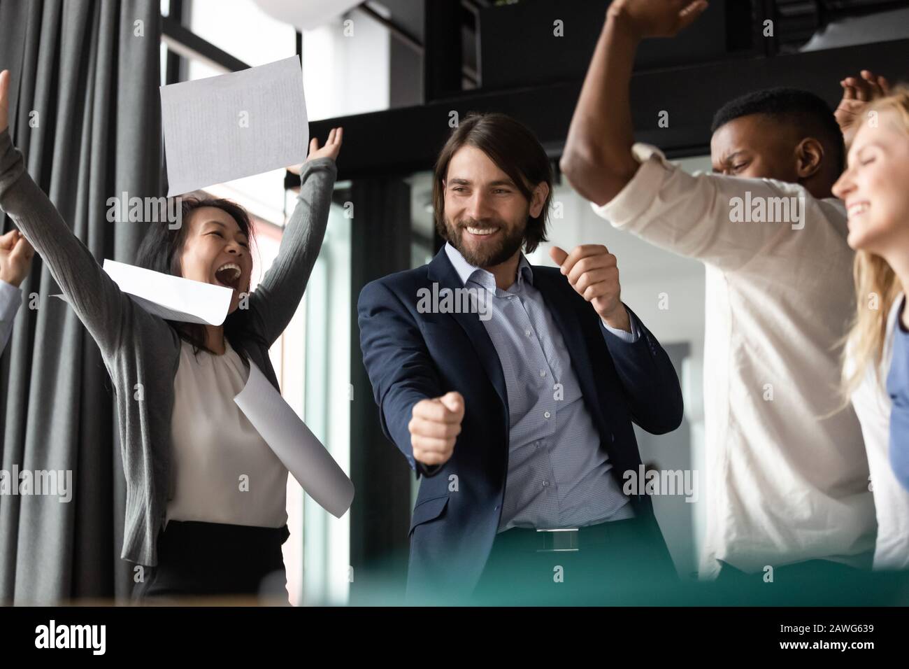 Excited diverse coworkers celebrating success, throwing papers ...