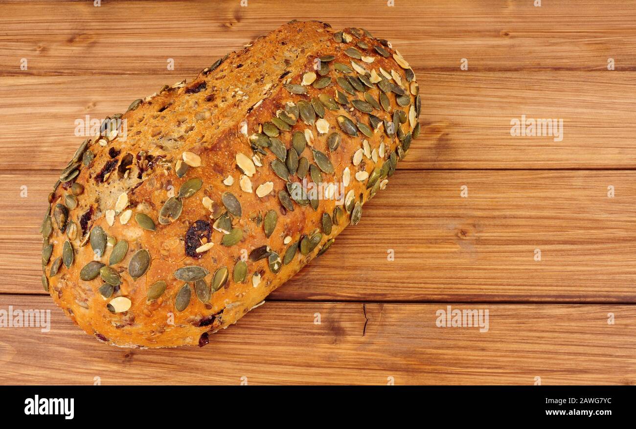 Rustic pumpkin seed covered crusty bloomer loaf on a wooden background ...